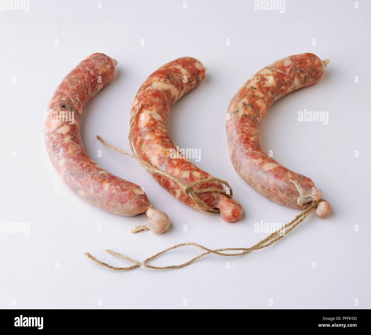 Garlic and herb salami sausages in casing tied with string at end Stock ...