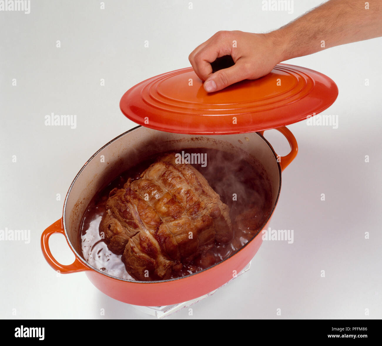 Placing lid on top of casserole dish containing silverside of beef ...