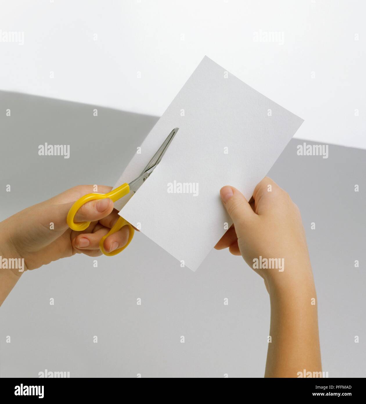 Girl's hand cutting strip from piece of white paper, close-up Stock ...