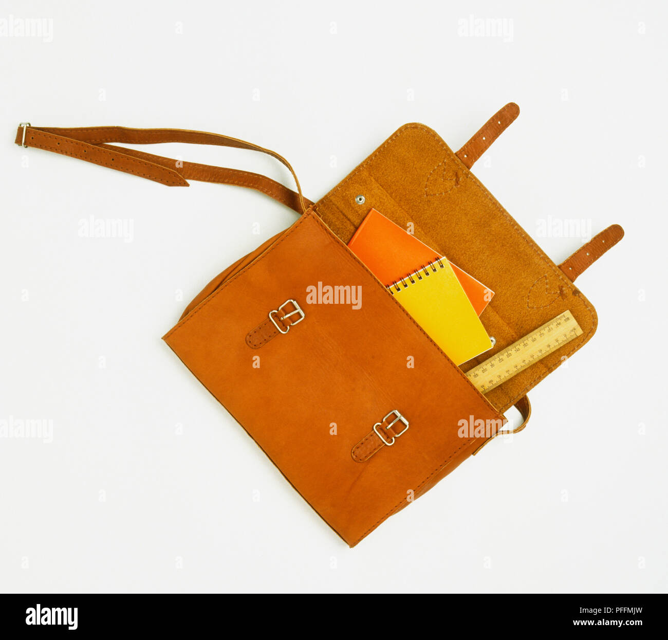 Tan leather satchel with ruler and school books inside, view from above ...