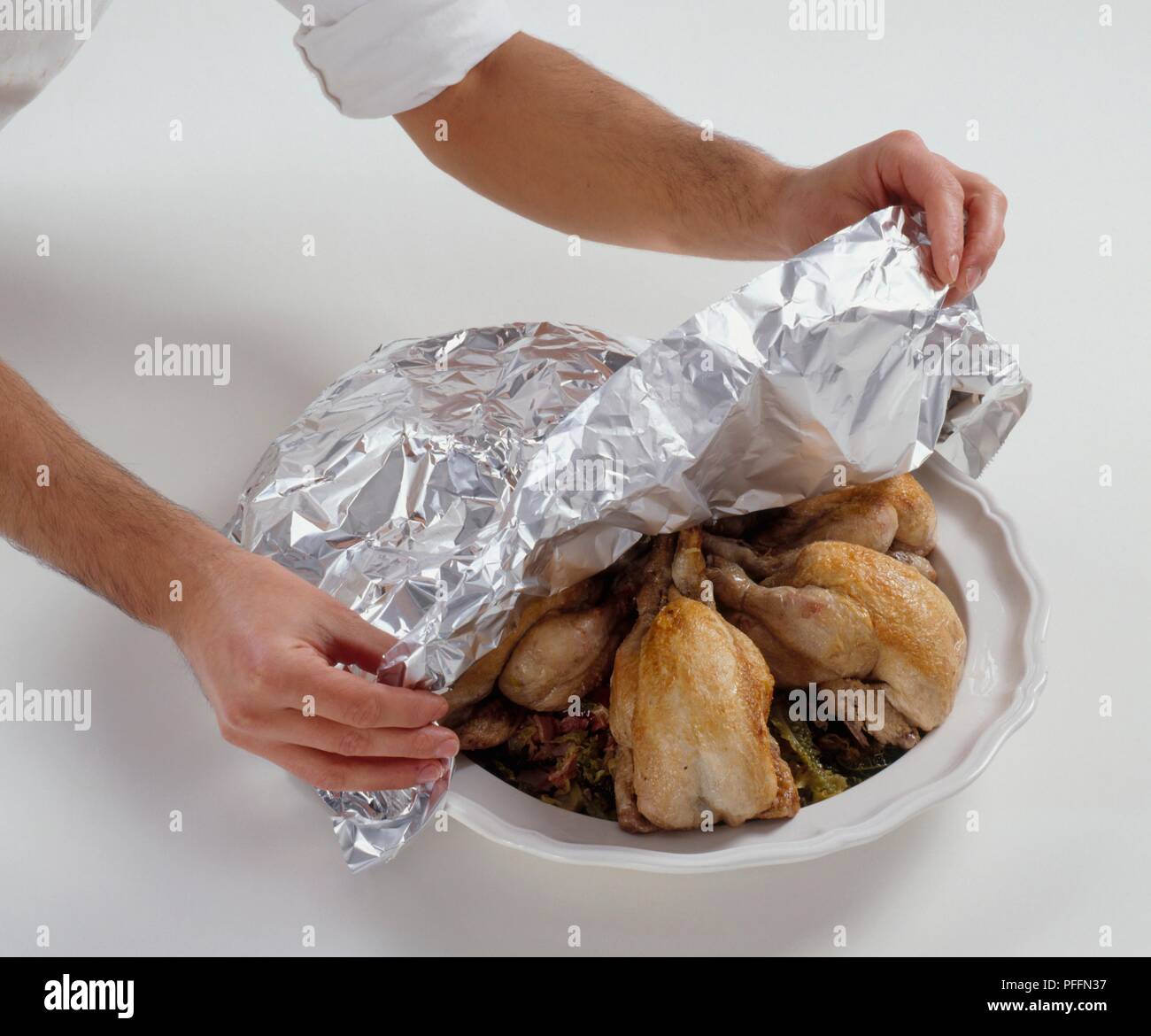 Covering roasted poussin in serving dish with foil Stock Photo - Alamy