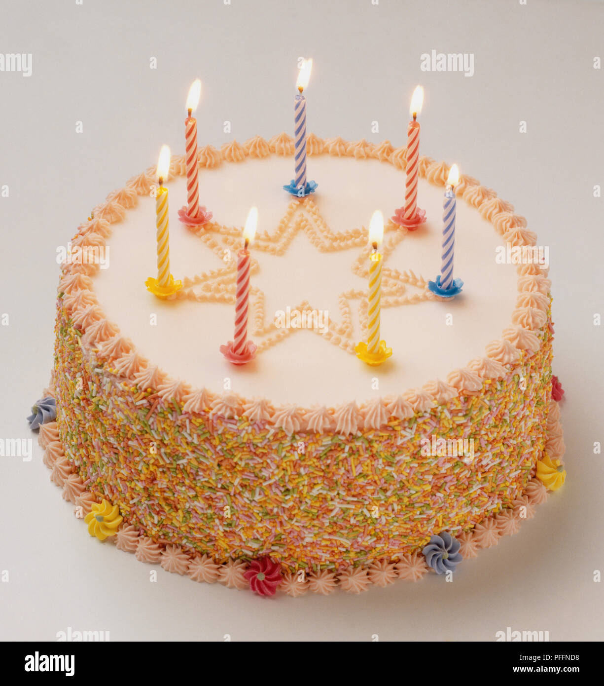 Iced and frosted birthday cake with seven lit candles, close up Stock ...