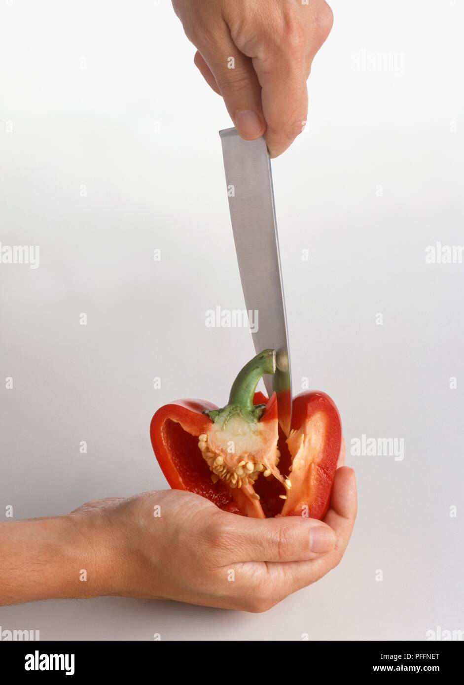 Cutting out stalk and core from halved red bell pepper Stock Photo - Alamy