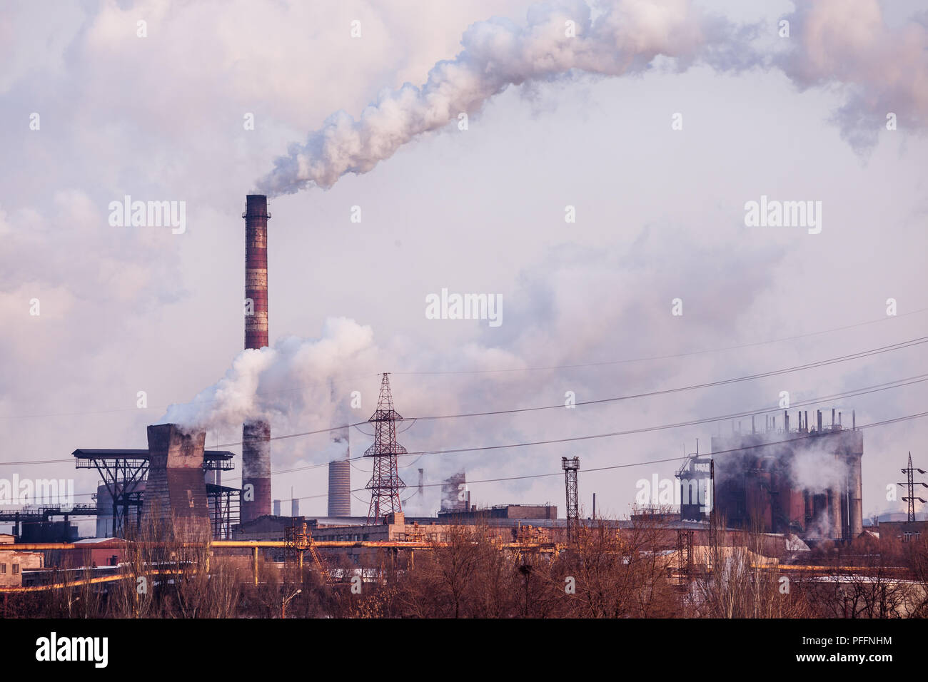 smoke stacks in a working factory emitting steam, smog and air ...
