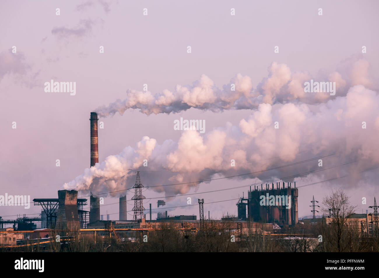 smoke stacks in a working factory emitting steam, smog and air ...