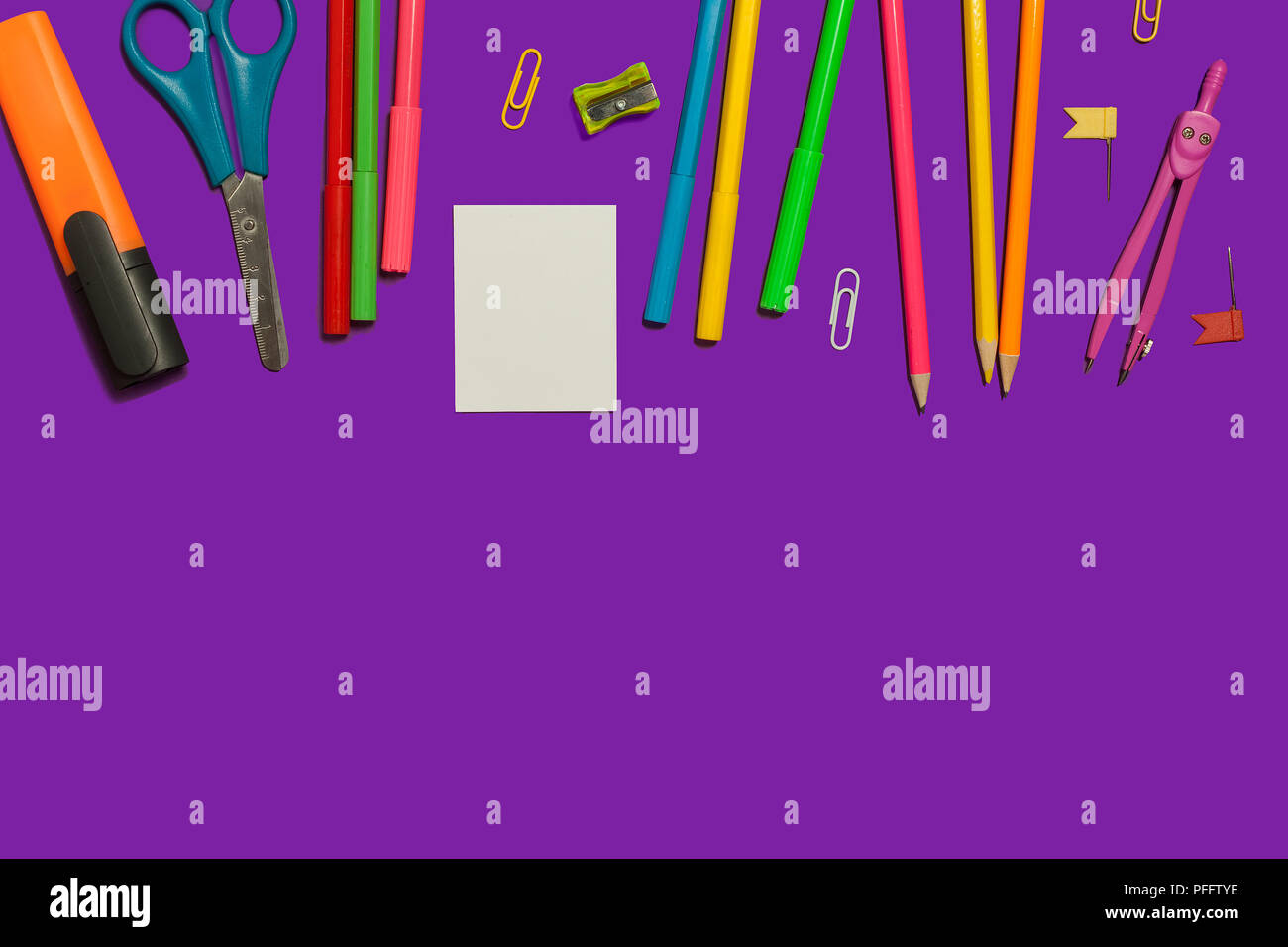 row of various school and office supplies and gadgets lying on a purple ...