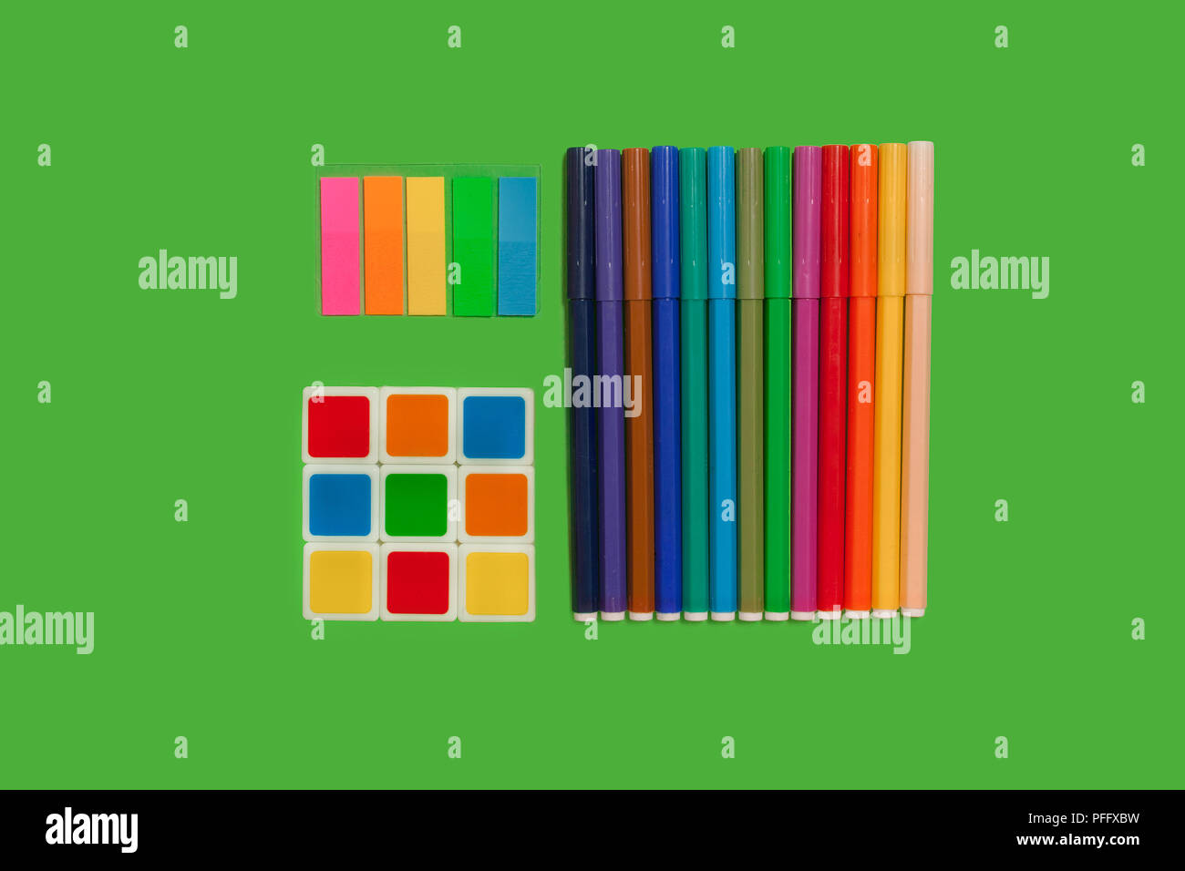 colorful felt pens, stickers and watercolour paints lying on a green ...