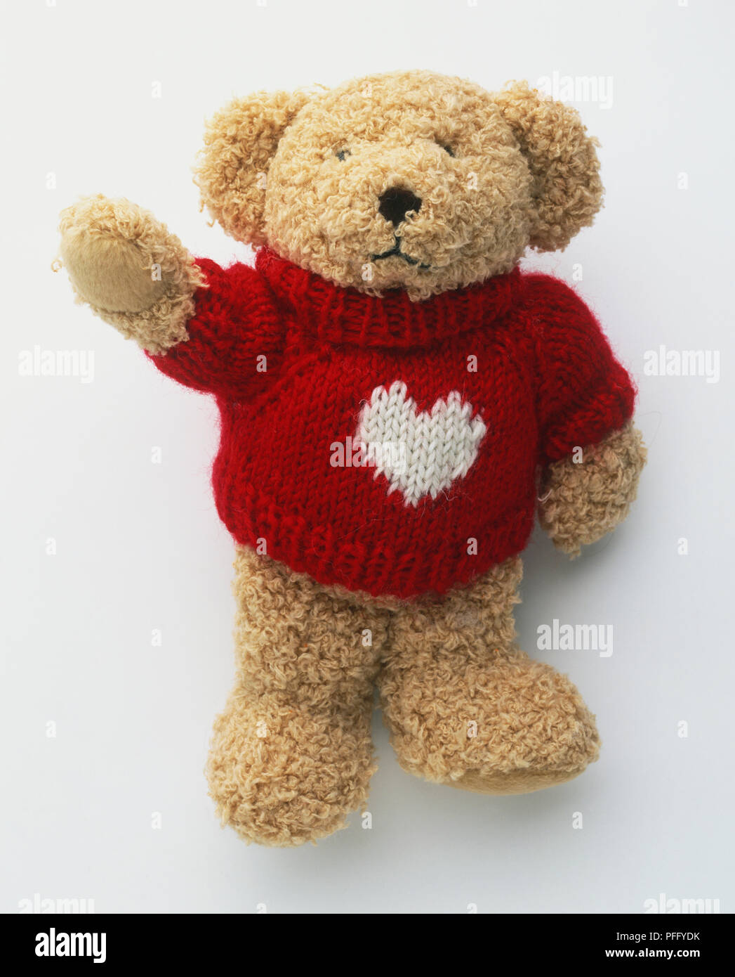 Yellow teddy bear wearing knitted red jumper with white heart on the ...