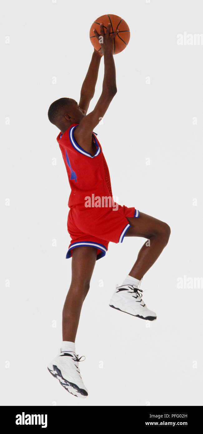 Boy reaching highest point of lay-up and preparing to release ball ...
