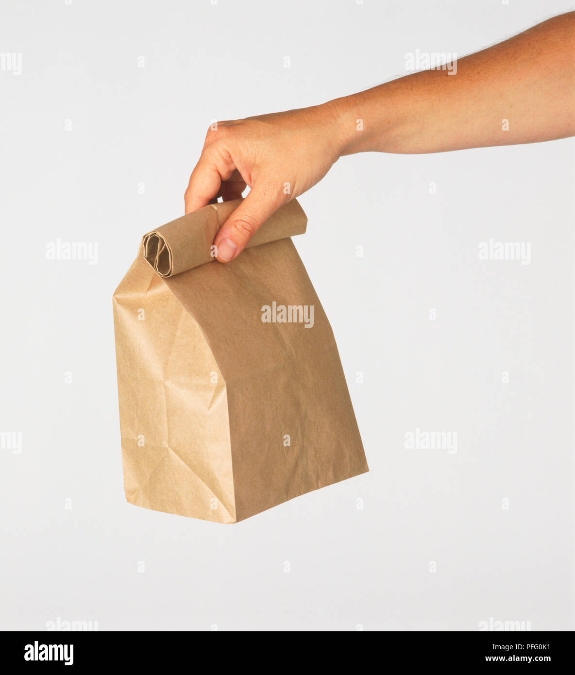 Hand holding brown paper bag Stock Photo - Alamy