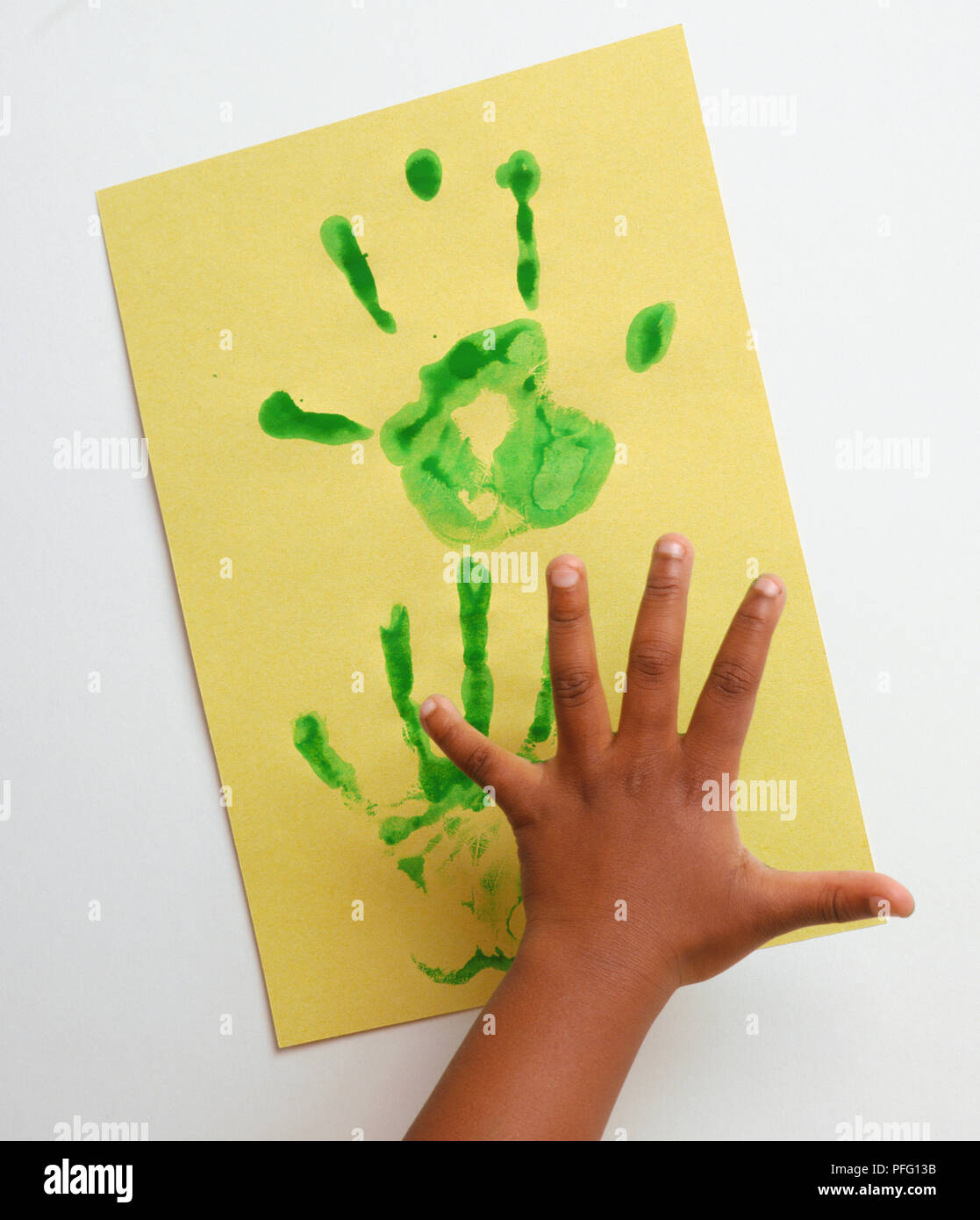 Picture of a child's hand making a green handprint on a piece of paper ...