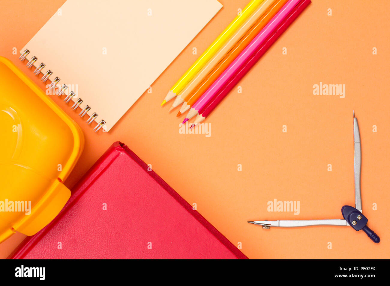 Book, lunch box, notebook, color pencils and compass on pink background ...