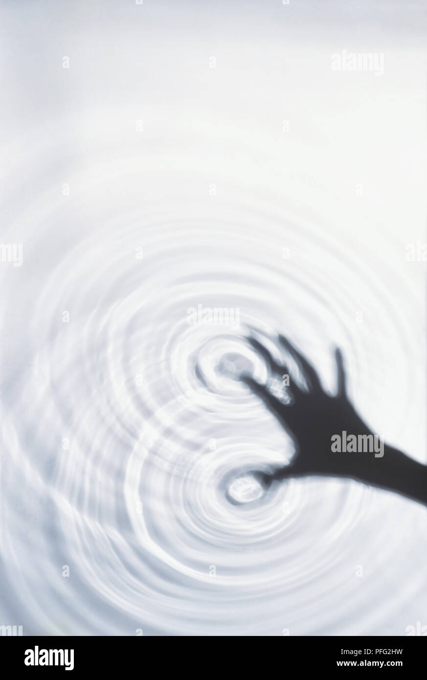 The shadow of a hand with thumb and forefinger tapping the surface of ...