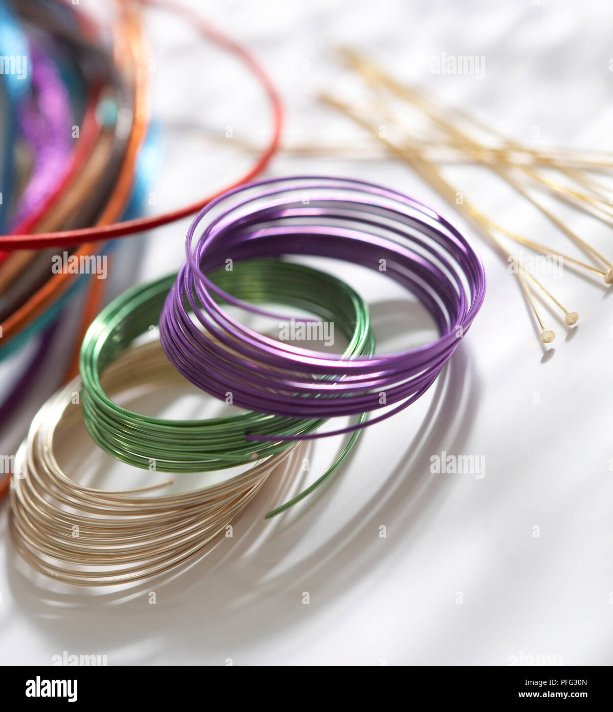 Three packs of coloured metal wire, head pins and thongs in background ...