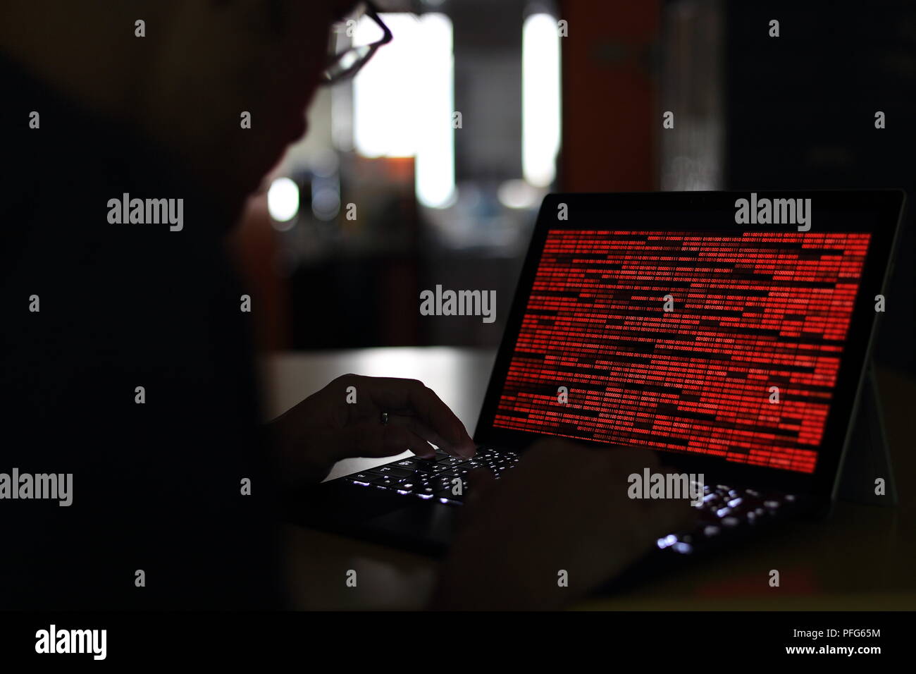 Computer Hacker Silhouette Typing On Computer In A Dark Room Working On Binary Code Technology