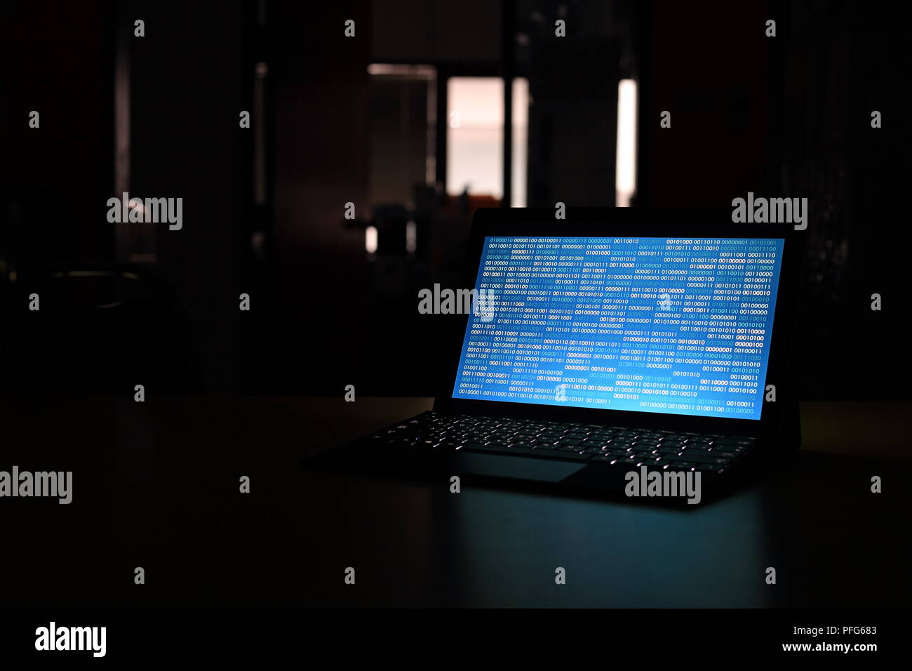 Computer Hacker silhouette typing on computer in a dark room. Working on blue binary code ...
