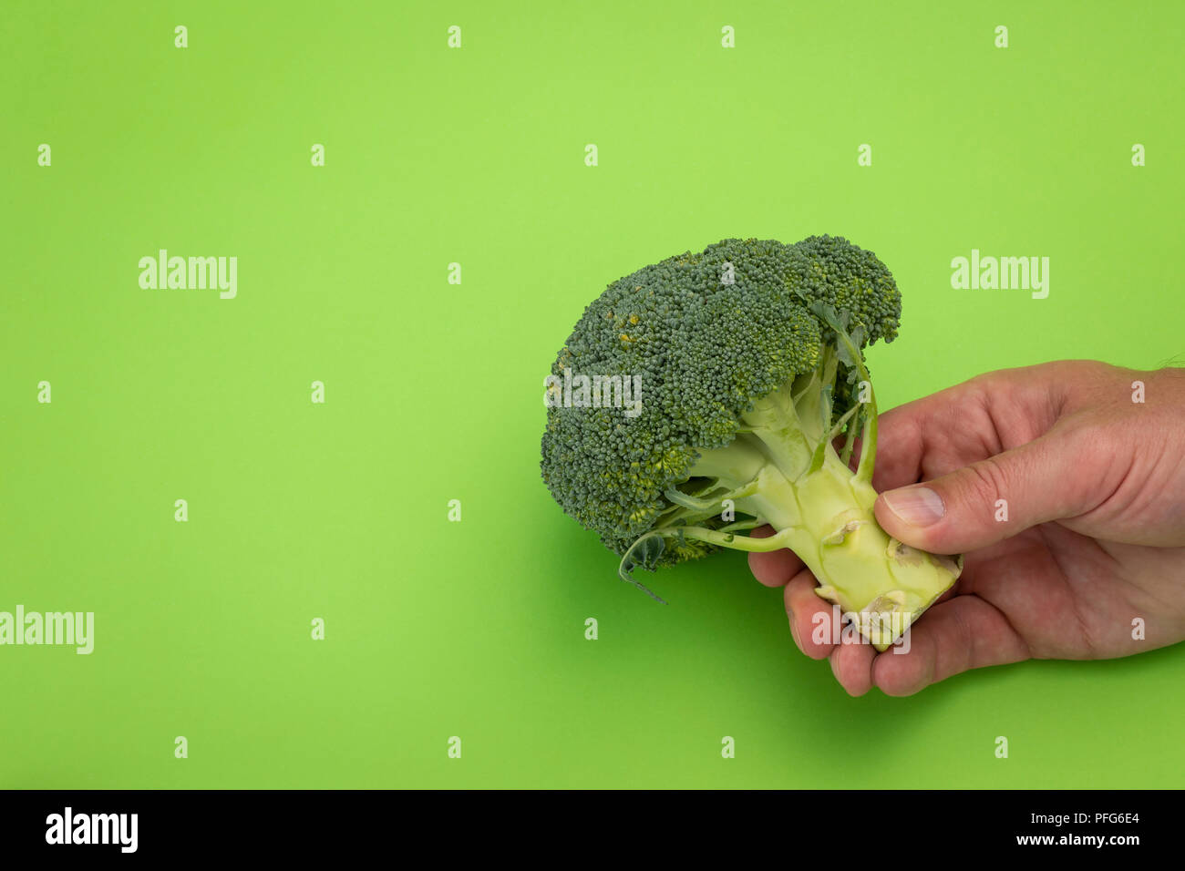 Men's hand holding piece of broccoli on green background Stock Photo ...