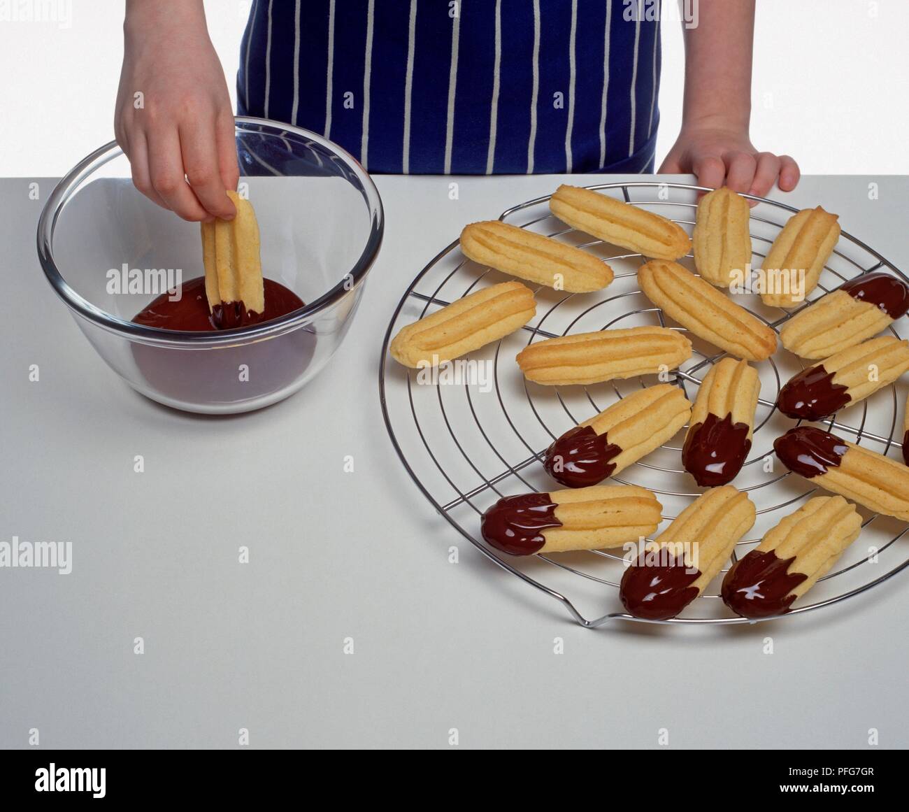 Biscuits being dipped into melted chocolate and placed onto cooling ...
