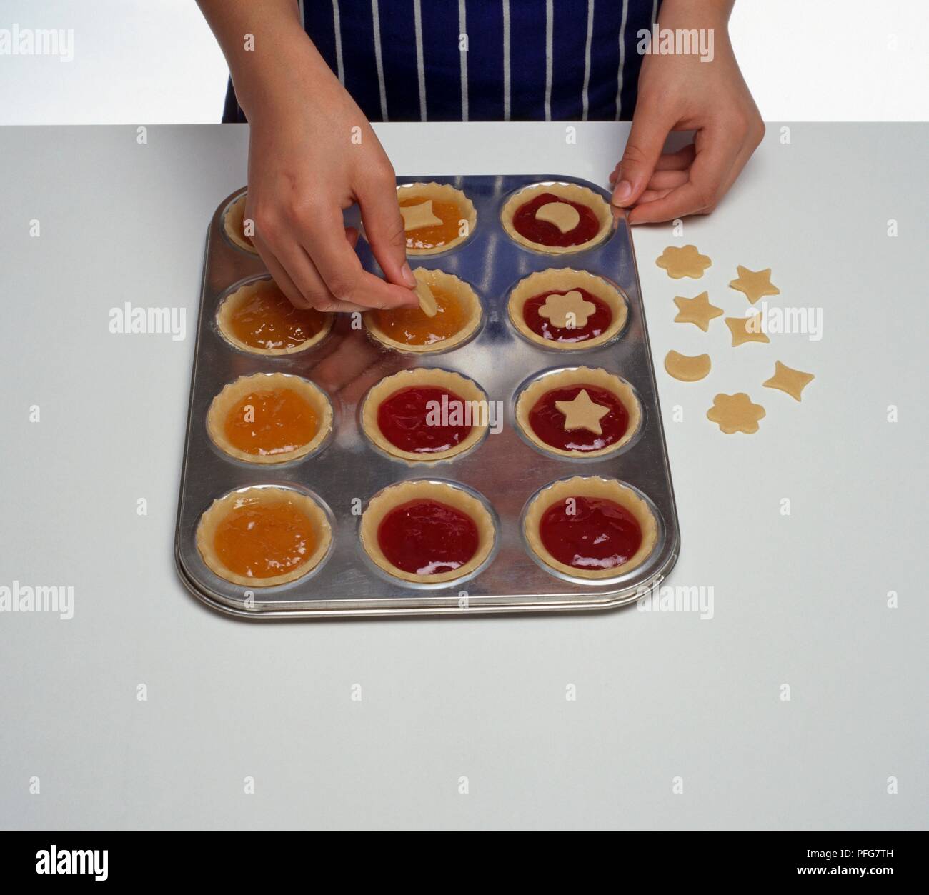 Jam tarts being decorated with pastry shapes Stock Photo - Alamy