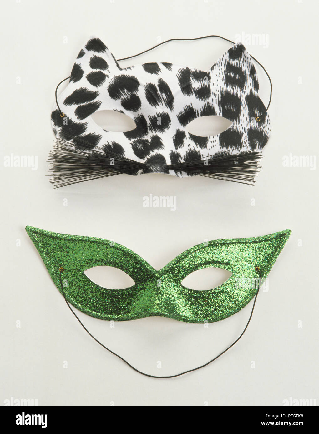 Two face masks one black and white spotted and a green glitter mask ...