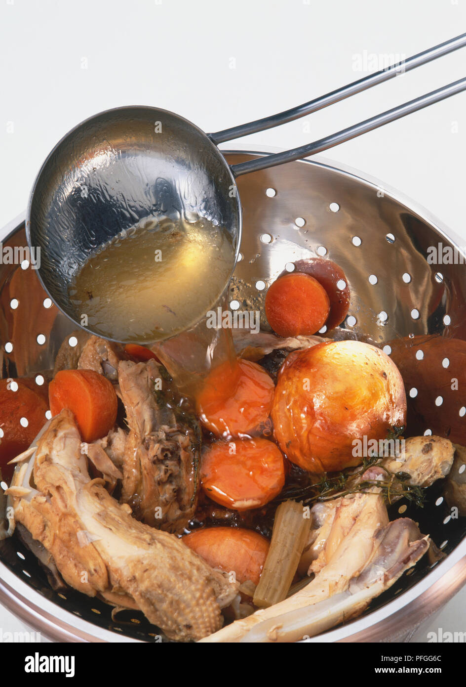 Making chicken stock, ladle pouring stock over pieces of vegetables ...