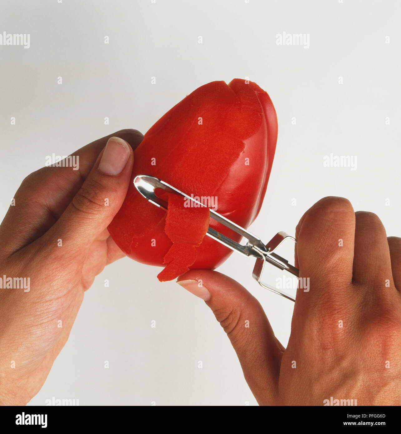 Using a vegetable peeler to remove the skin from a red pepper Stock ...