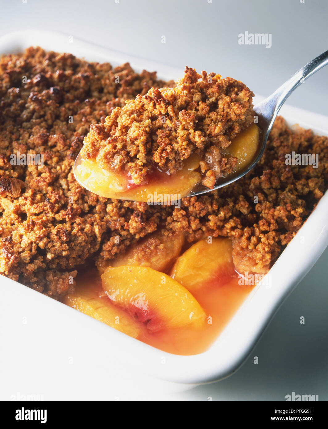 Peach crumble in a baking dish and on a spoon Stock Photo - Alamy