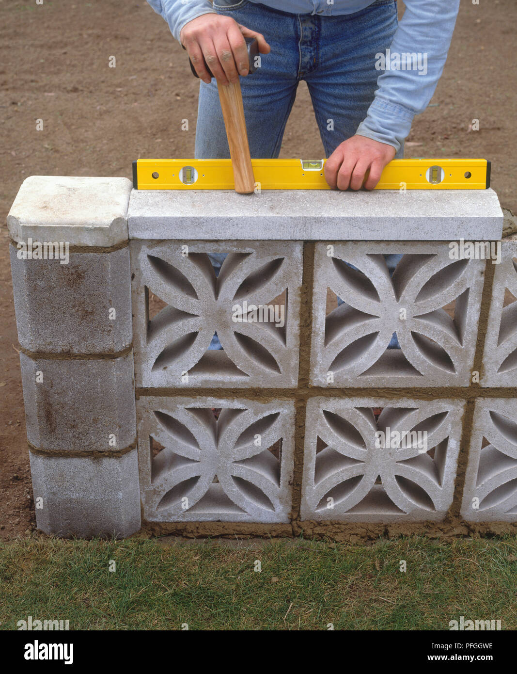 Man holding spirit level and hammer on top of garden wall Stock Photo ...