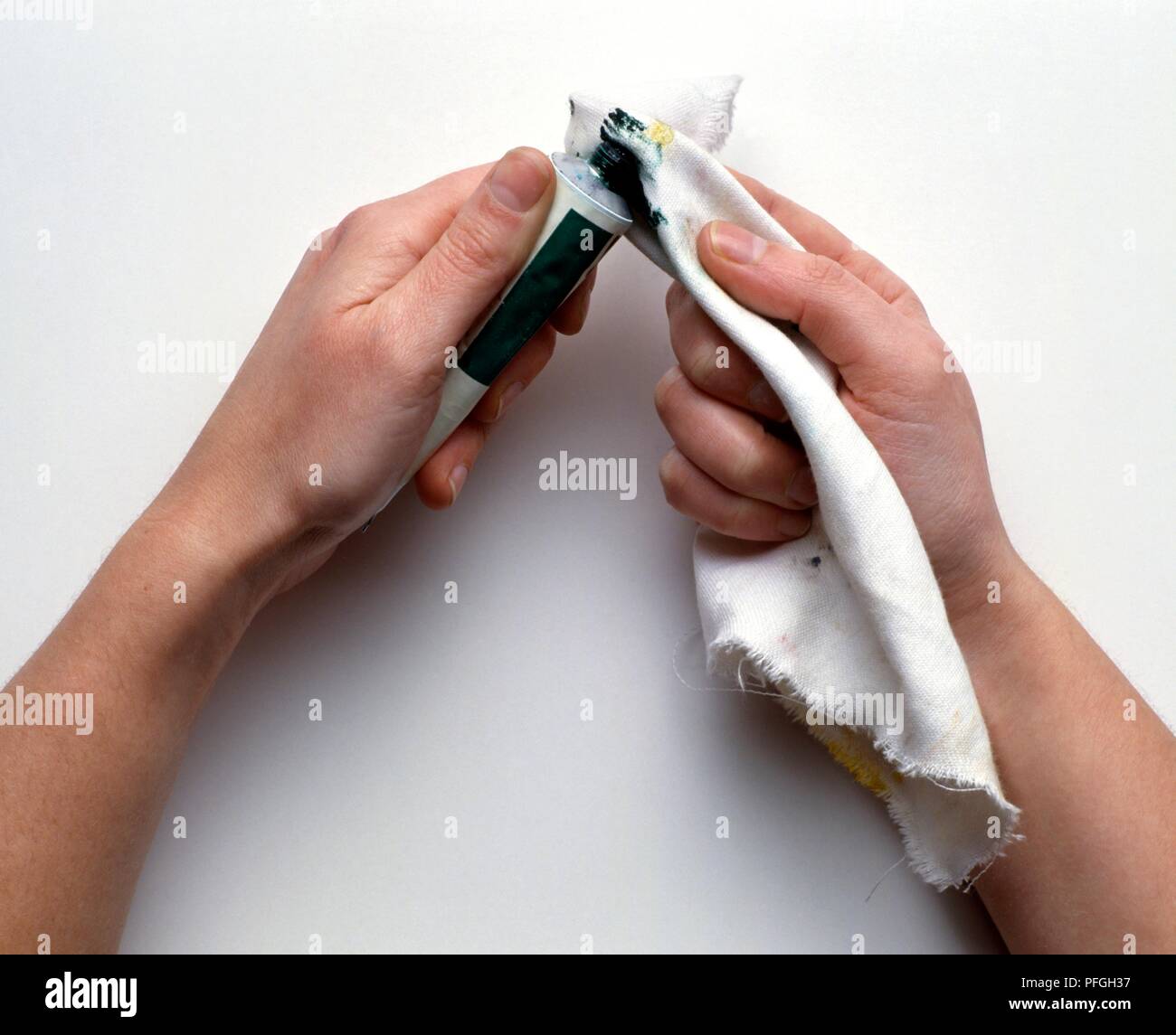 Cleaning excess paint away from top of tube of oil paint with white ...