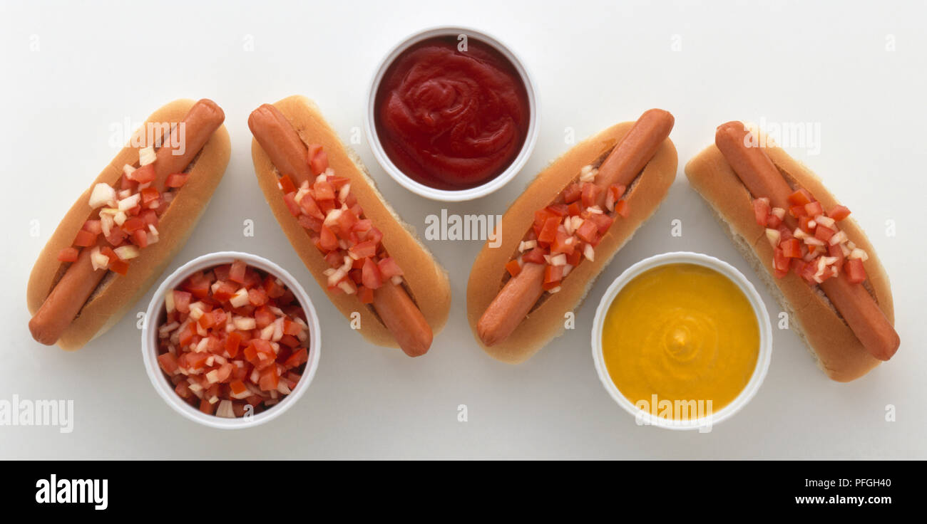 Hot dogs topped with tomato salsa, next to bowls of tomato ketchup ...