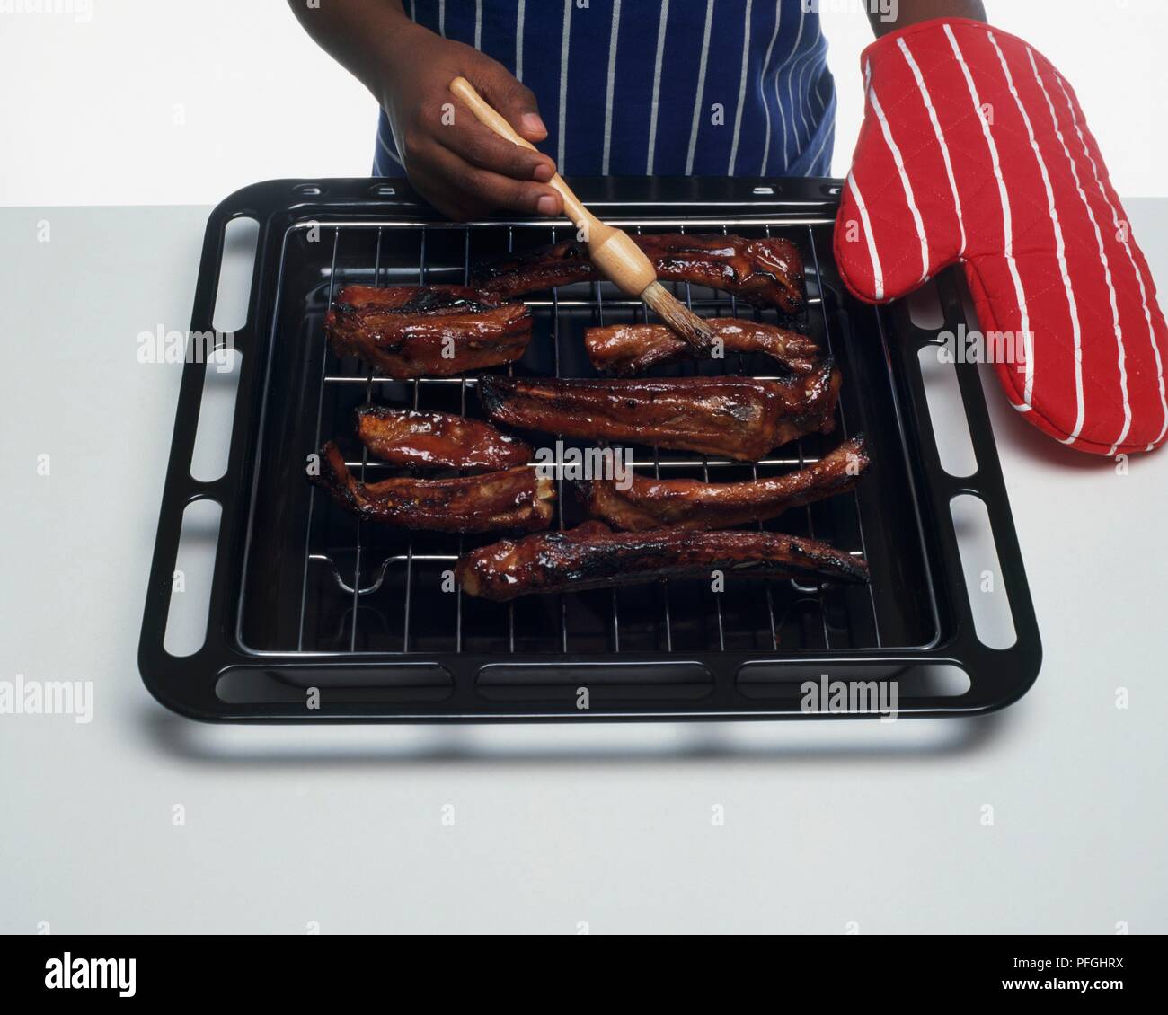 Boy's hand brushing spare ribs with basting brush, close-up Stock Photo ...