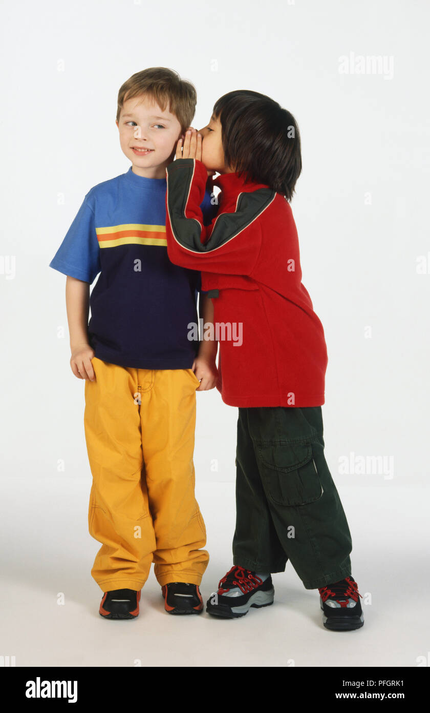 A boy whispering into another boy's ear Stock Photo - Alamy