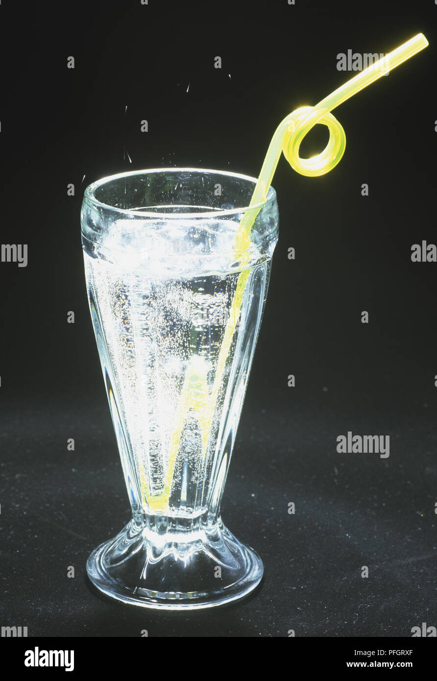Clear fizzy drink served in tall glass with curly yellow straw Stock ...
