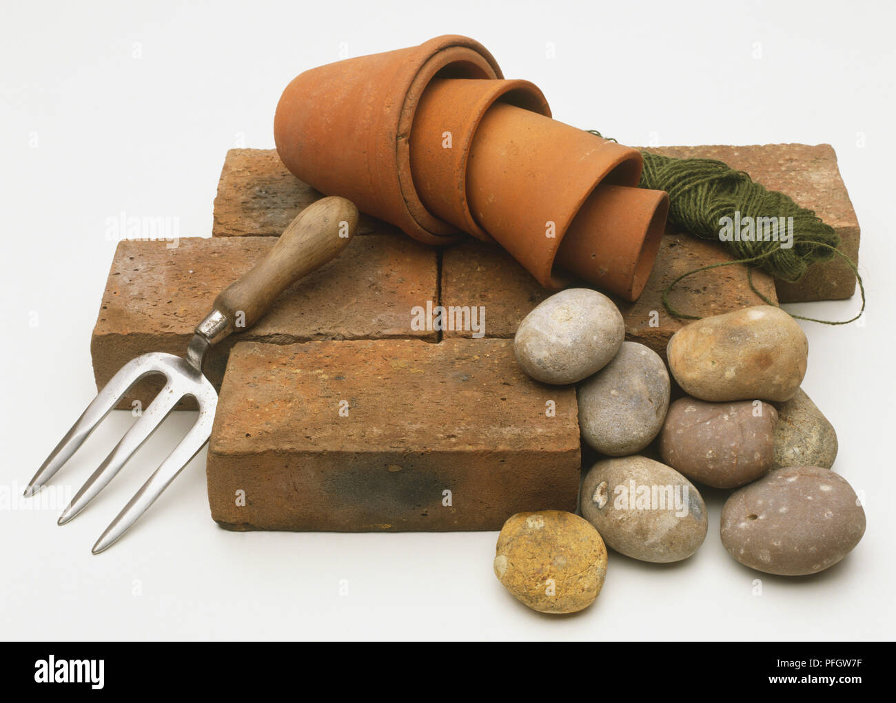 Pebbles, stacked plant pots, thread, bricks and fork Stock Photo - Alamy
