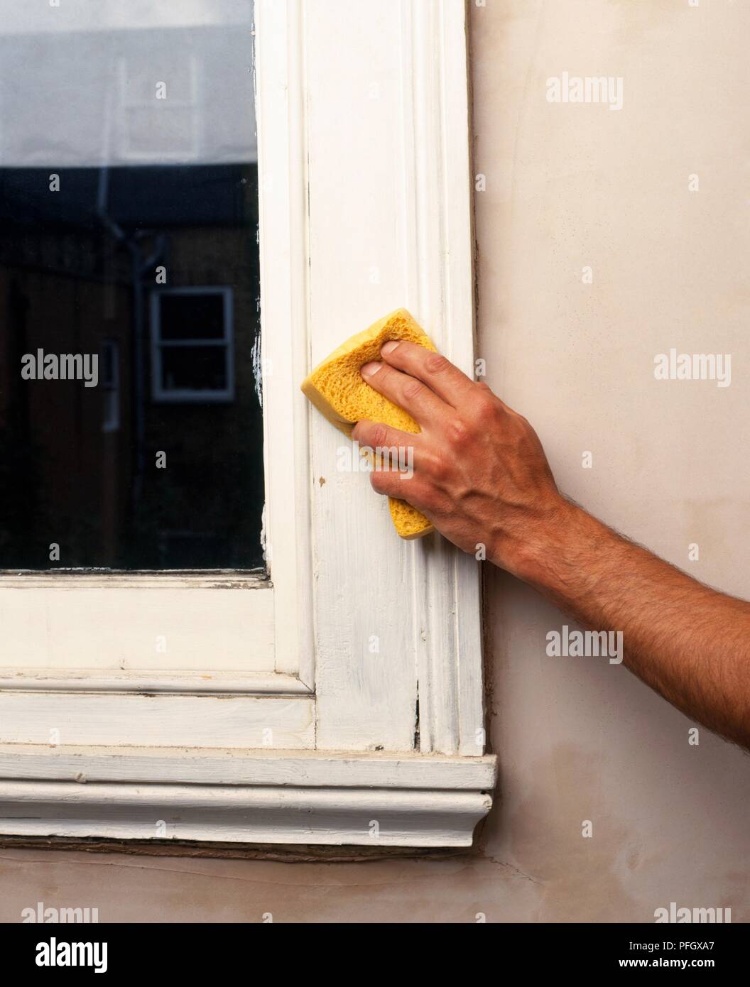 Preparing old window frame for fresh painting, wiping down with sponge ...