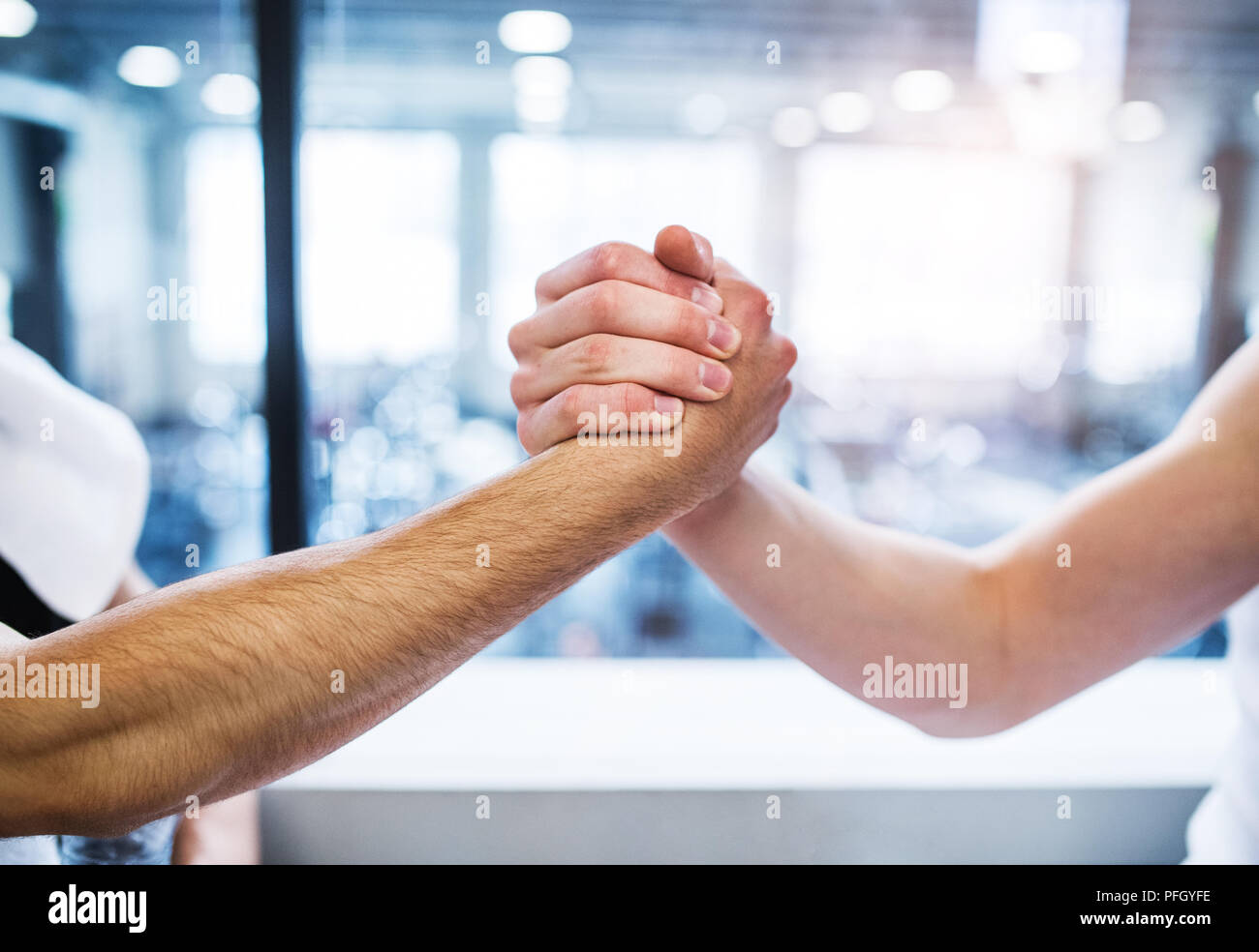 A friendly handshake of two young unrecognizable men in crossfit gym. A ...