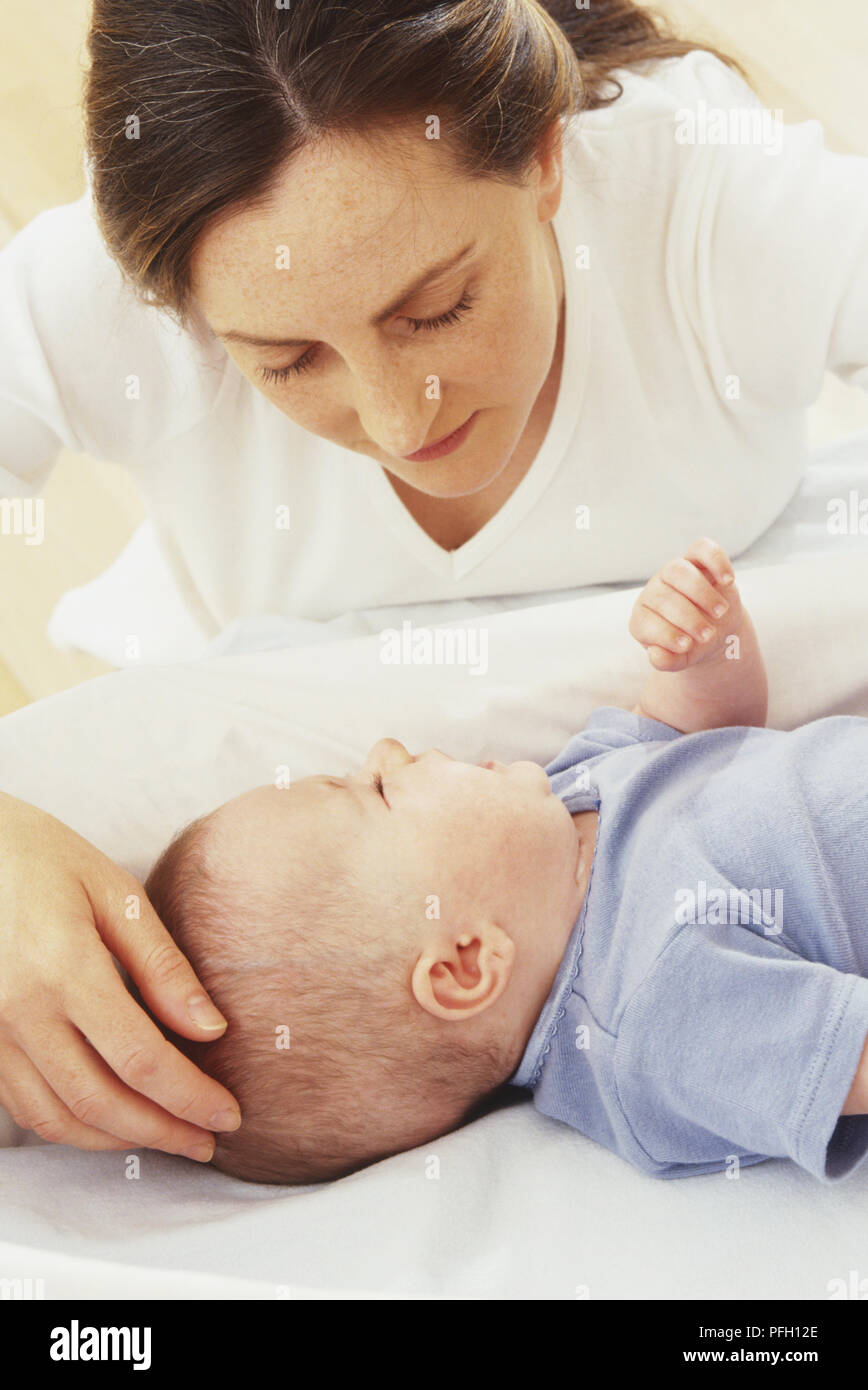 Woman leaning over baby girl lying on her back Stock Photo - Alamy