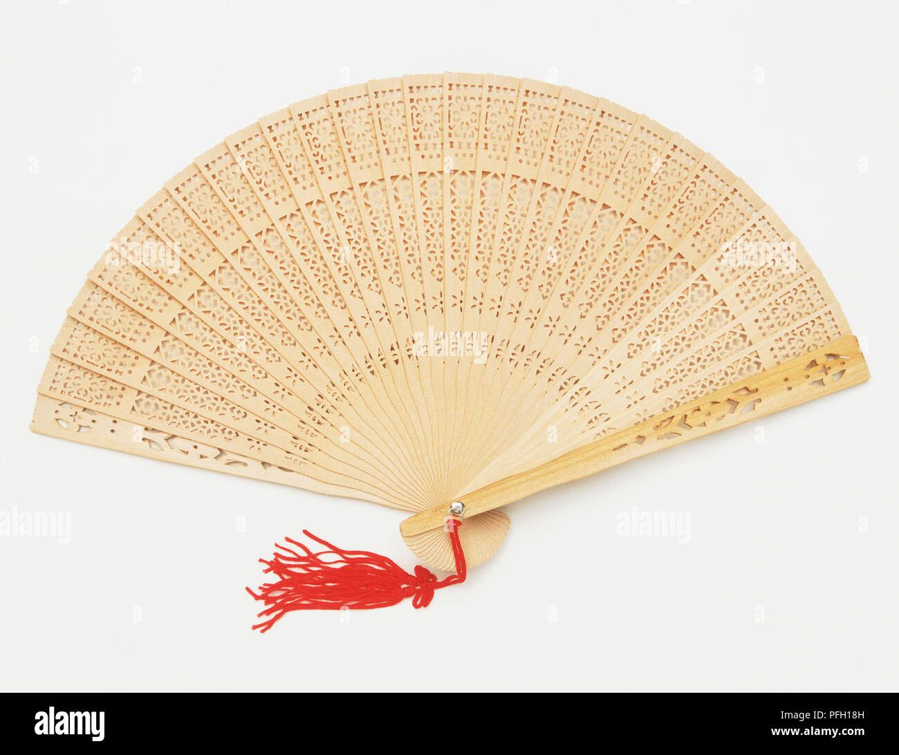 Wooden fan spread open, with hole pattern and red tassel Stock Photo ...