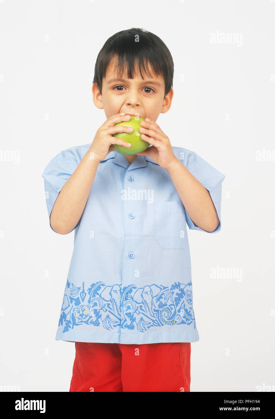 Boy holding apple with both hands and biting it Stock Photo - Alamy