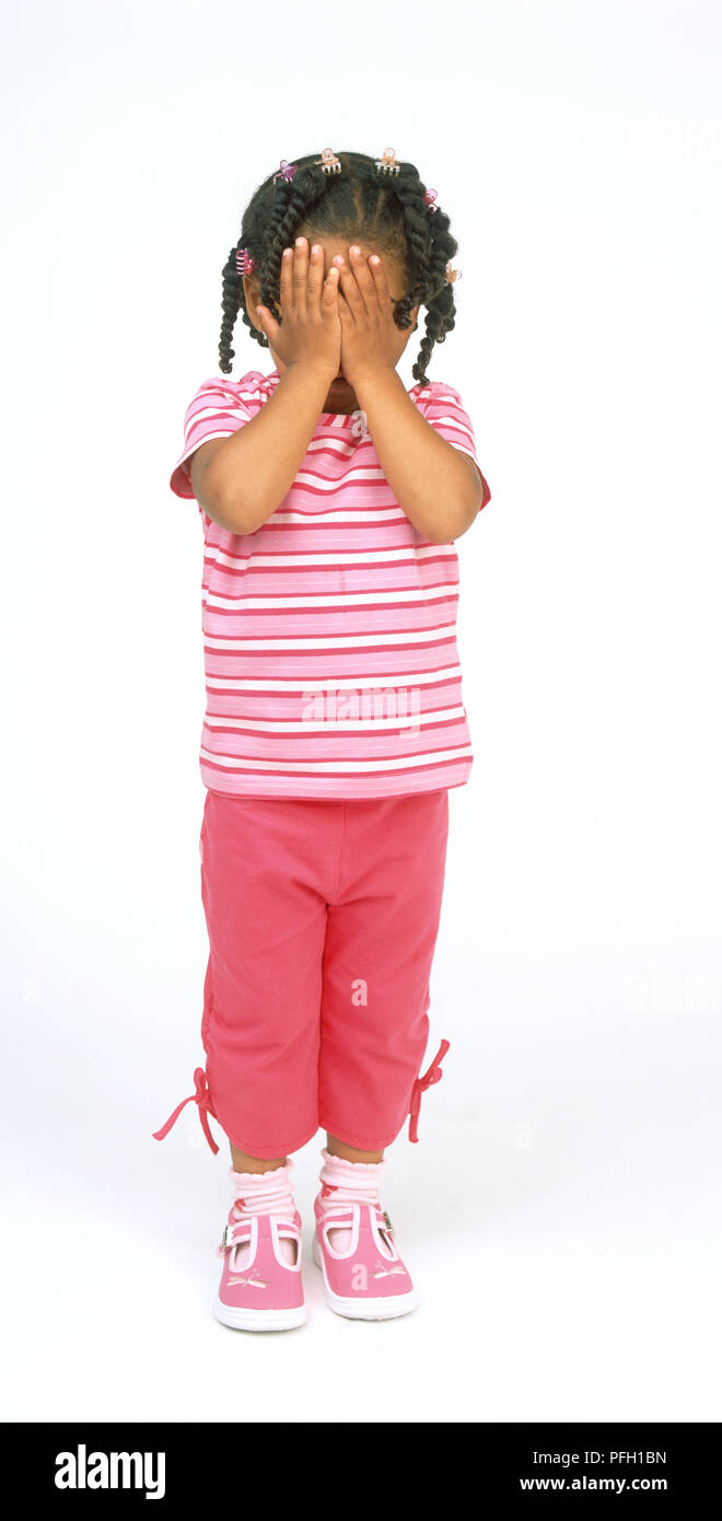 Girl standing with hands over her face Stock Photo - Alamy
