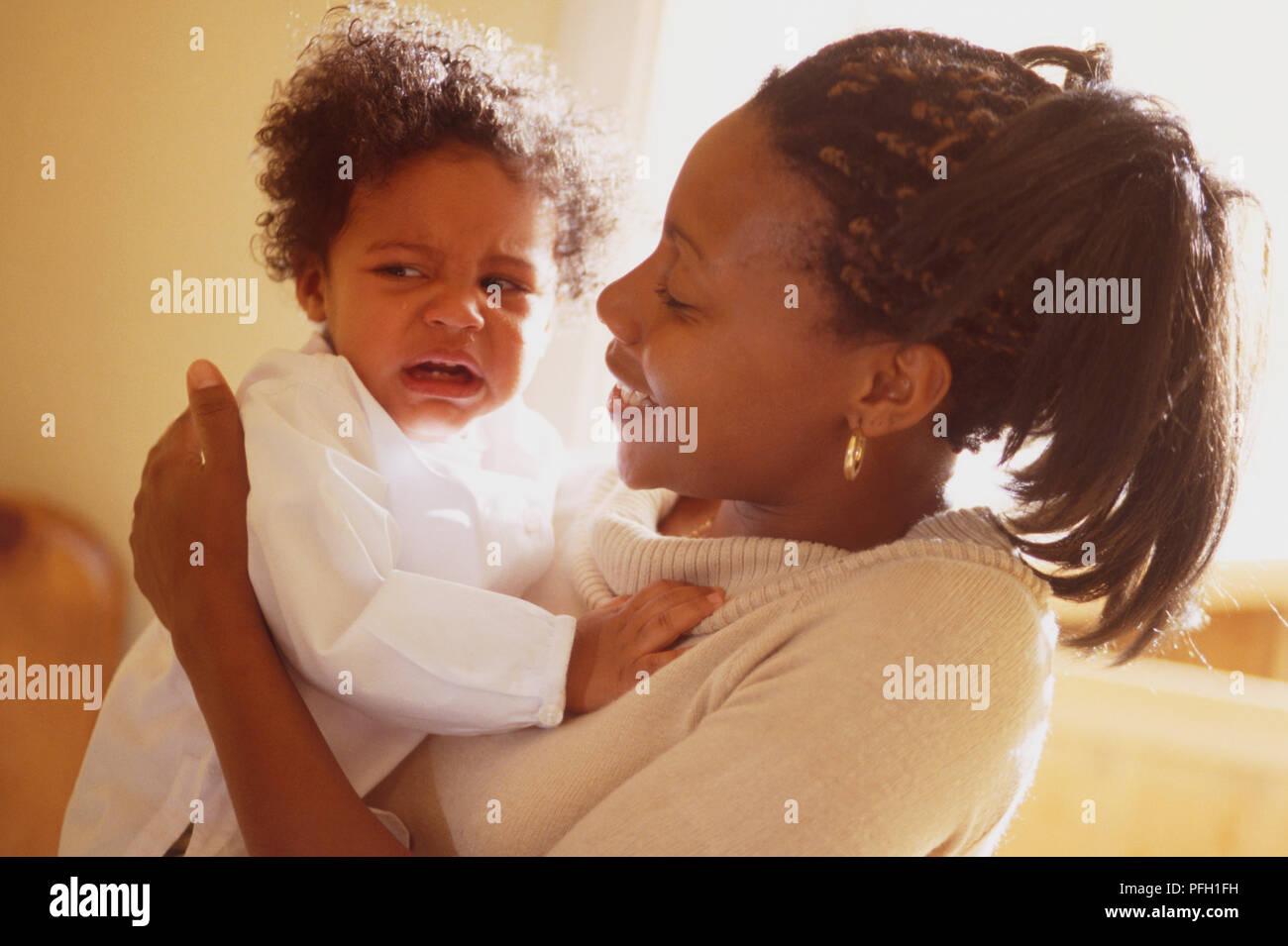 Woman holding a crying baby in her arms Stock Photo - Alamy