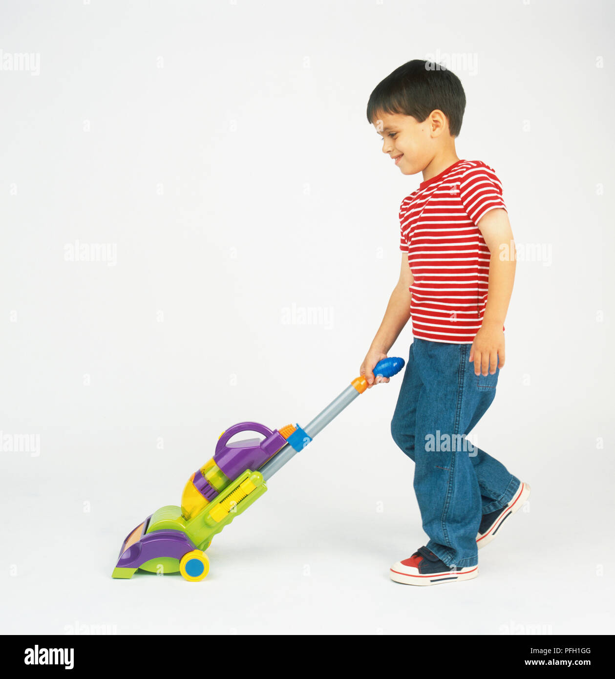 Boy pushing toy vacuum cleaner by handle Stock Photo - Alamy