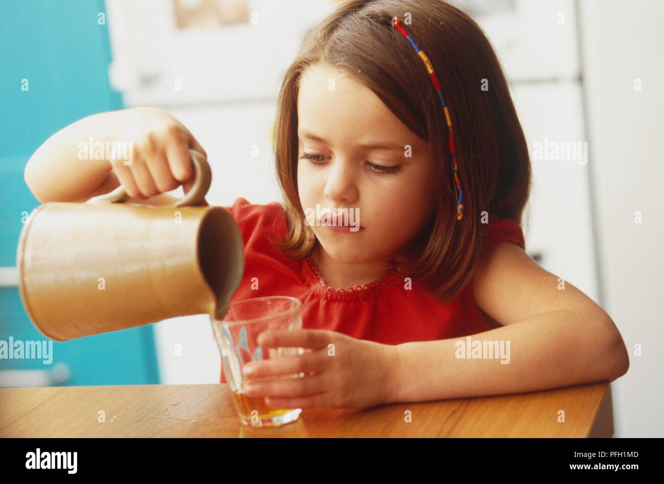Young girl pouring water into a glass from a jug Stock Photo - Alamy