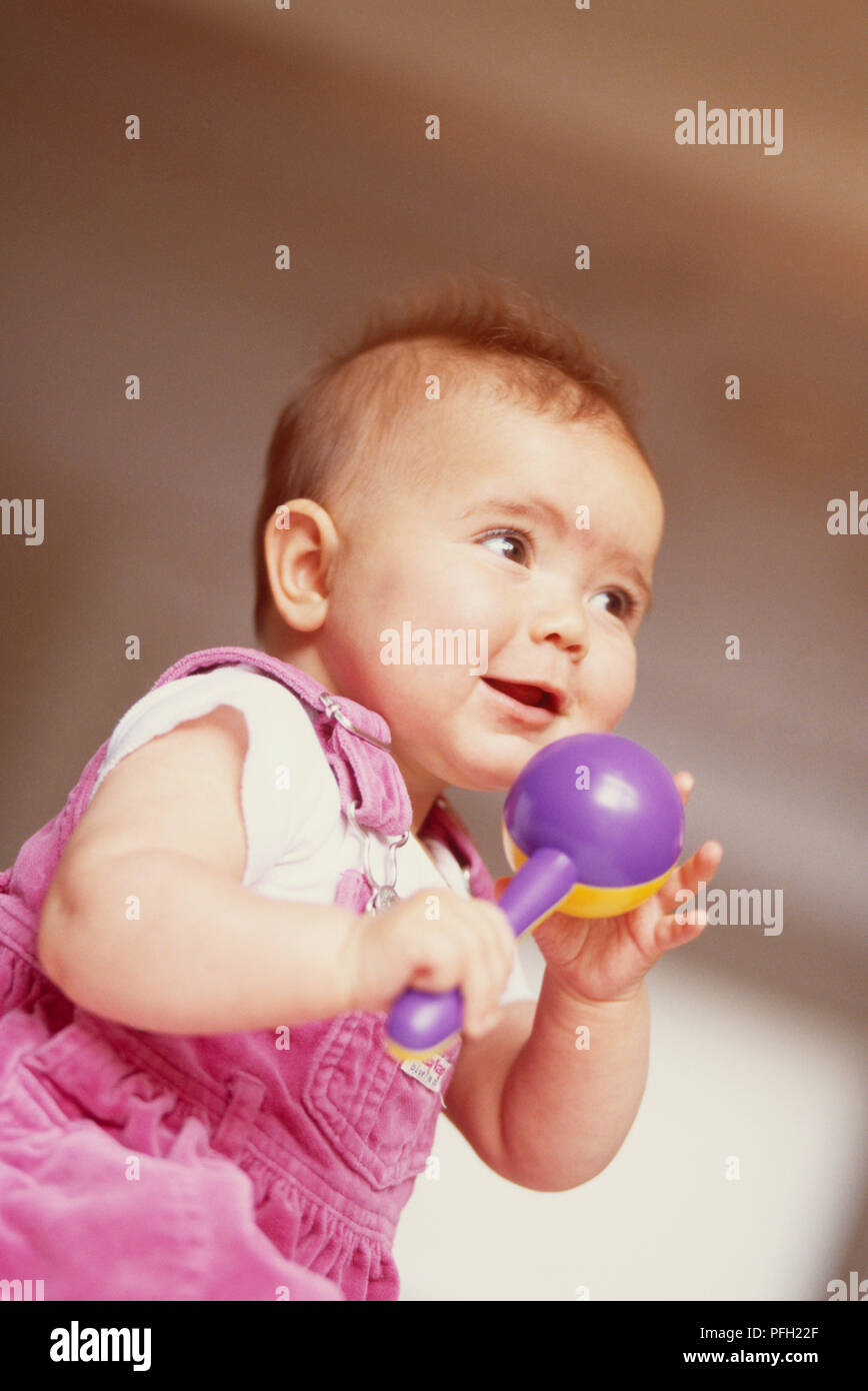 Baby holding a plastic purple rattle Stock Photo - Alamy