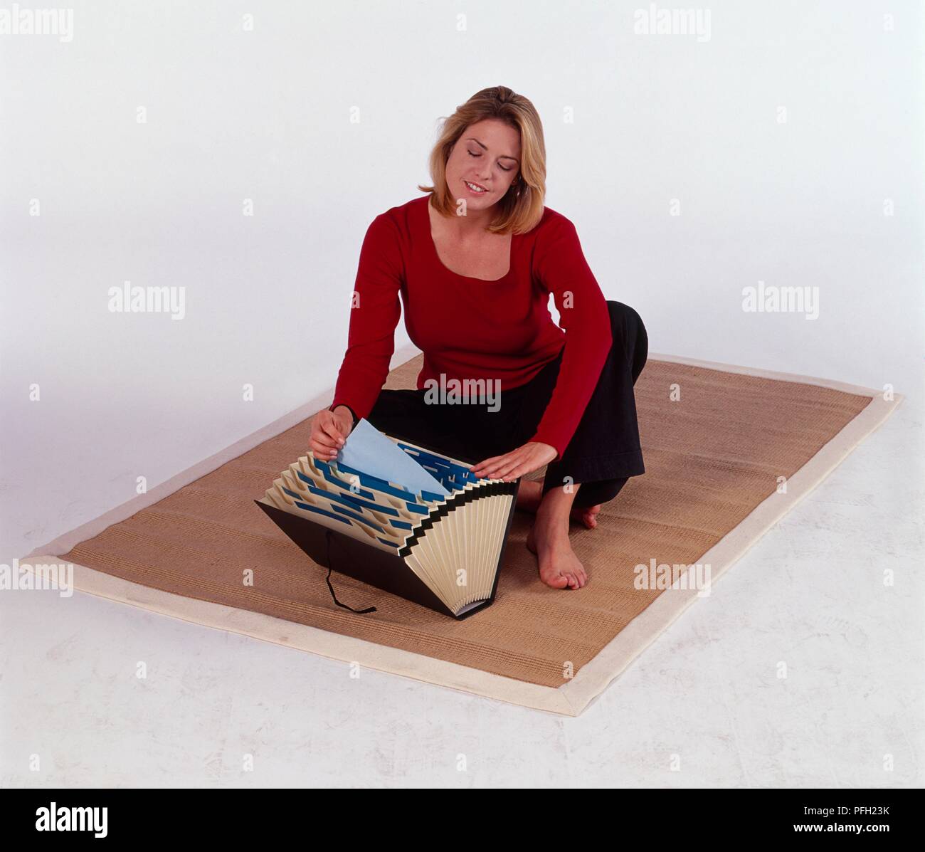 Woman sitting on rug looking through a concertina file Stock Photo - Alamy