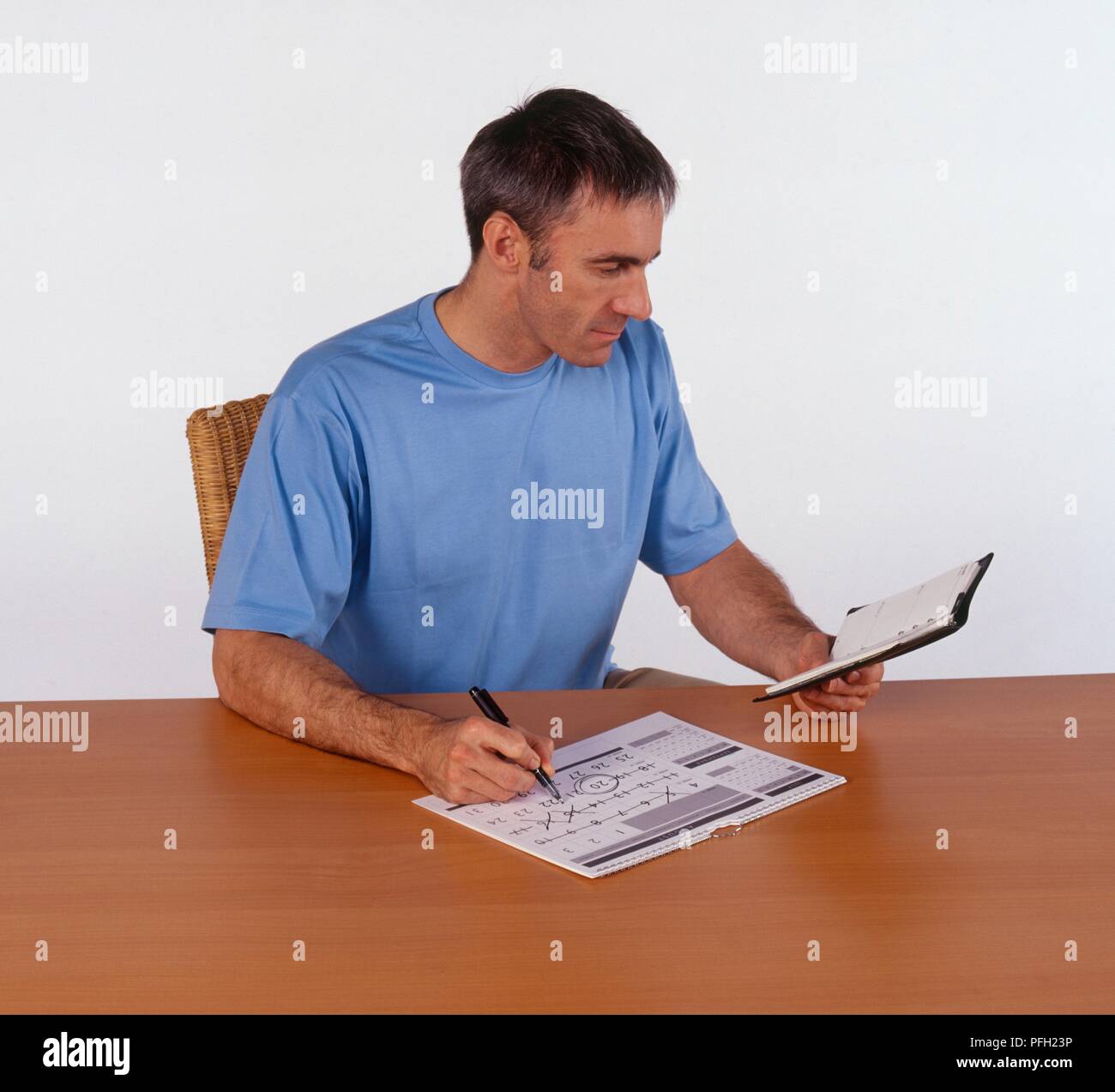 Man sat at desk checking his diary and calendar Stock Photo - Alamy