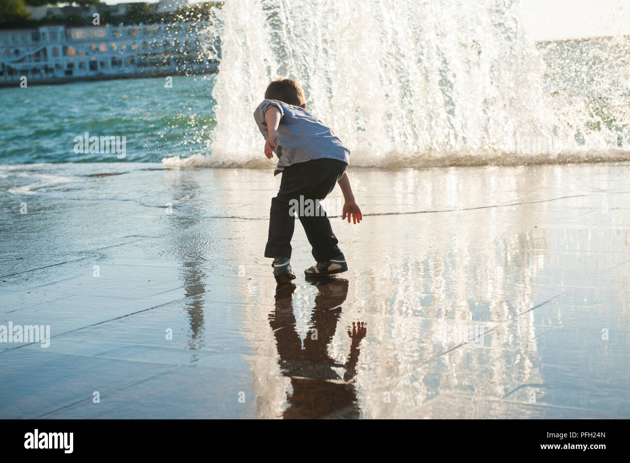 funny small kid escaping from huge wave in city port during autumn ...