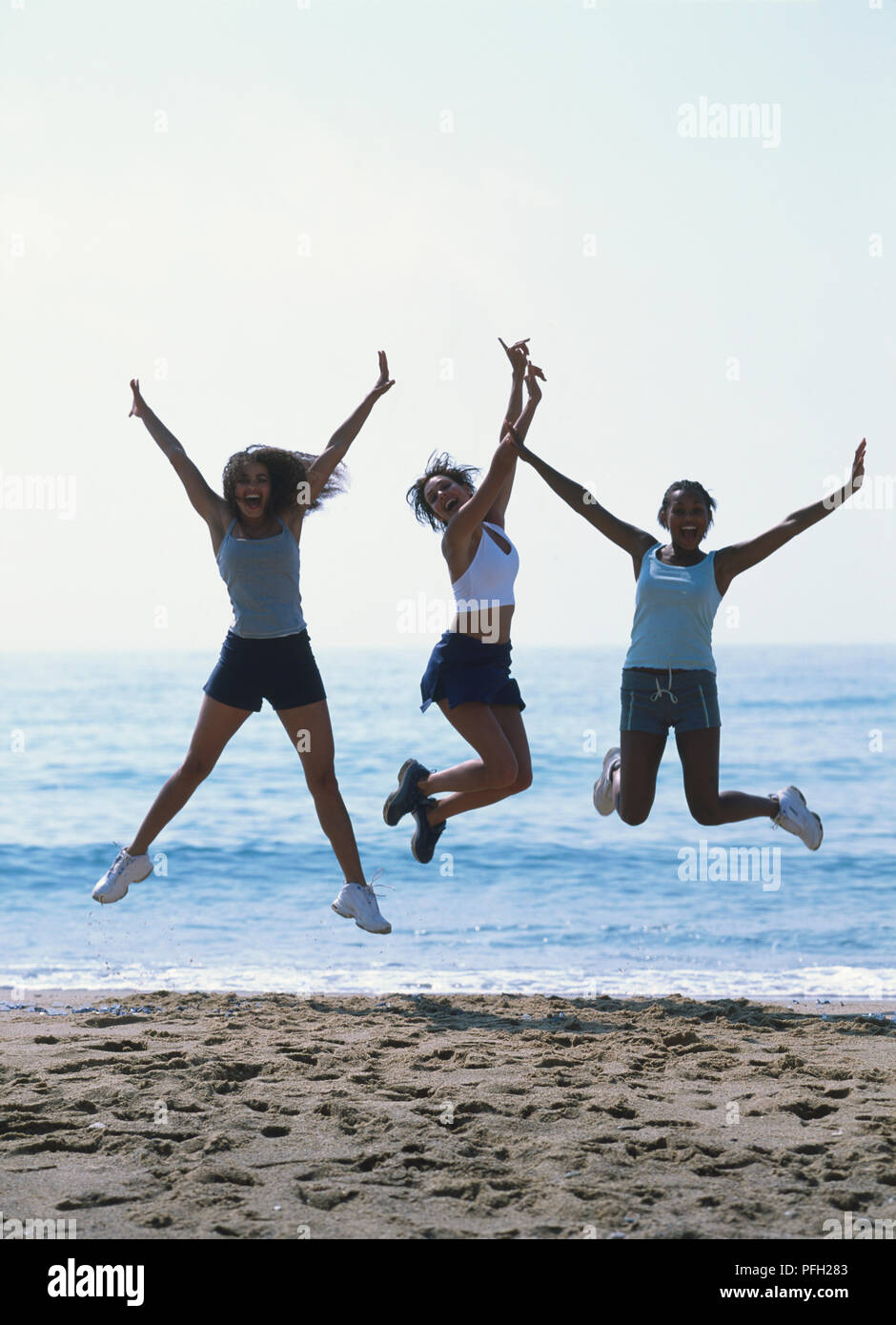 Three women jumping up in the air, beach and sea in background Stock ...