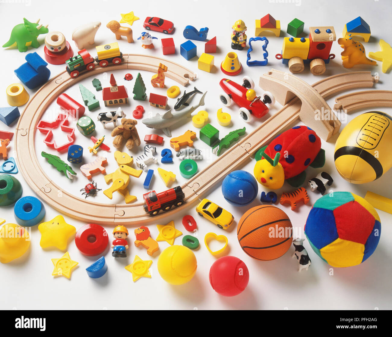 Selection of toys around a train track, including balls and animals ...