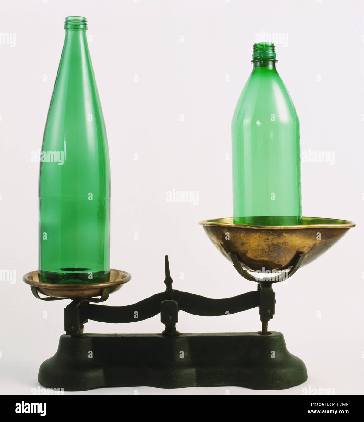 A green glass bottle and a green plastic bottle on a weighing scale ...